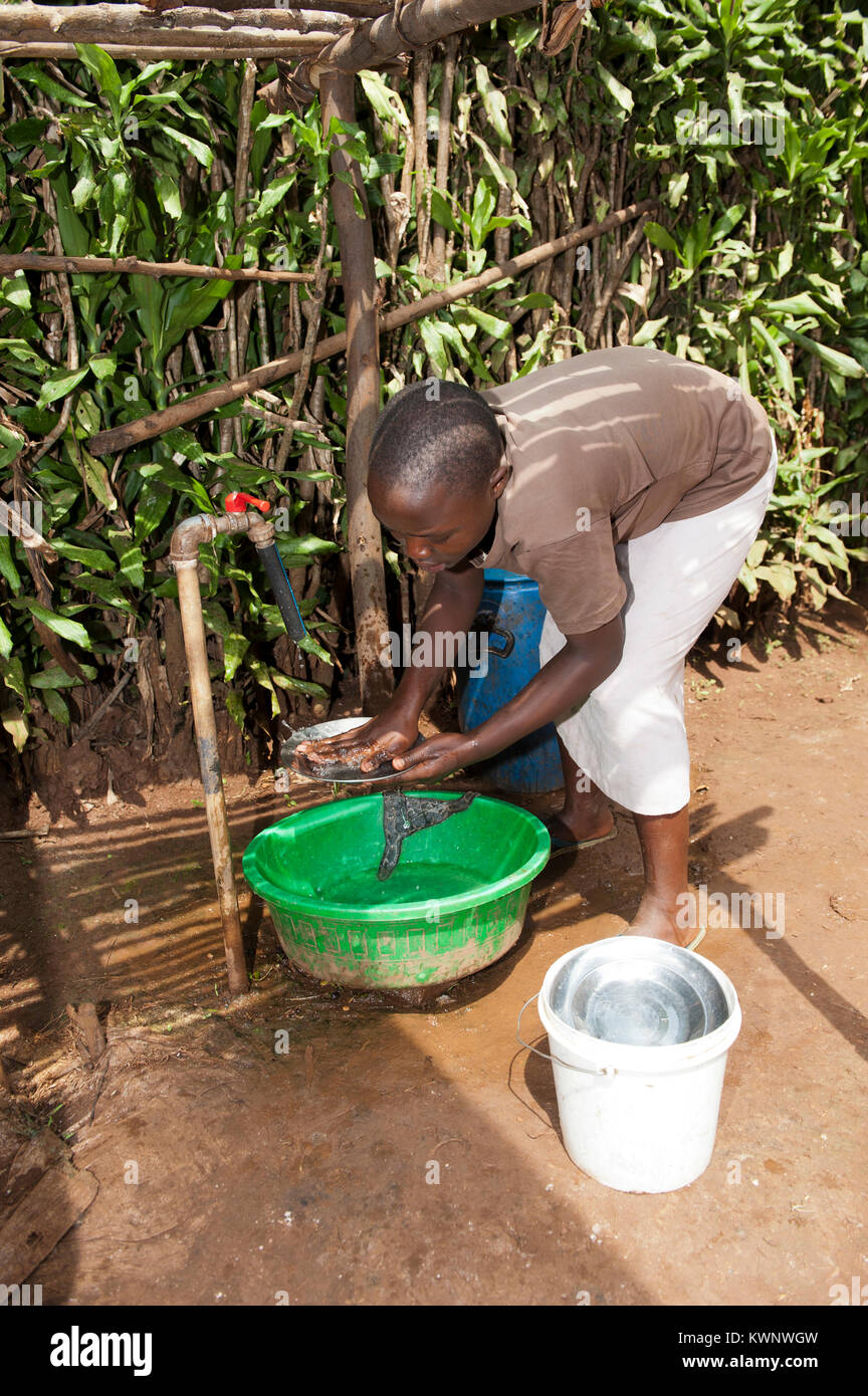 Girl washing kitchen utensils in water bowl, Rwanda Stock Photo - Alamy
