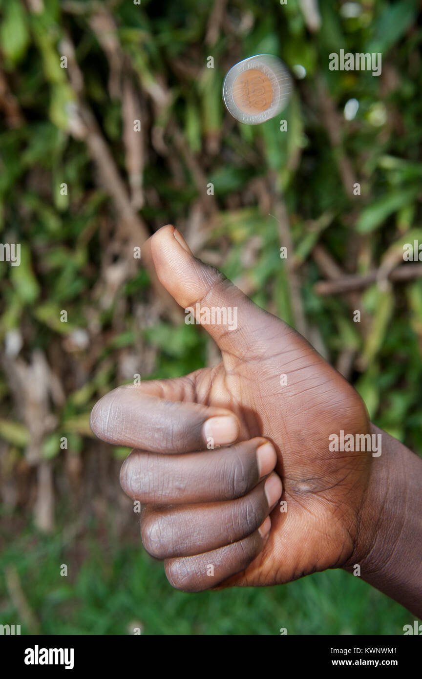 Person flipping a coin in Rwanda Stock Photo - Alamy