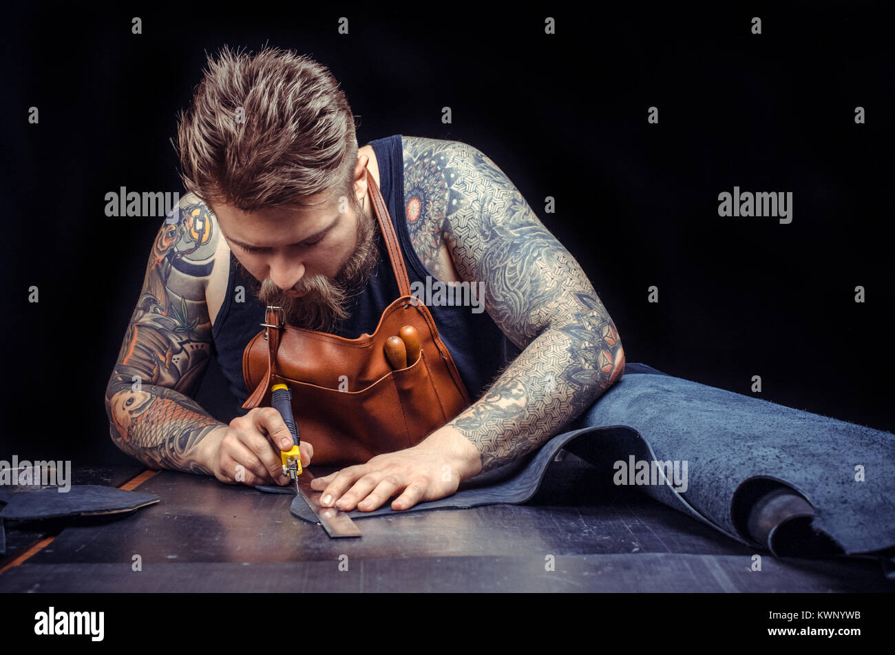 Man working with leather processes a workpiece from leather in the ...