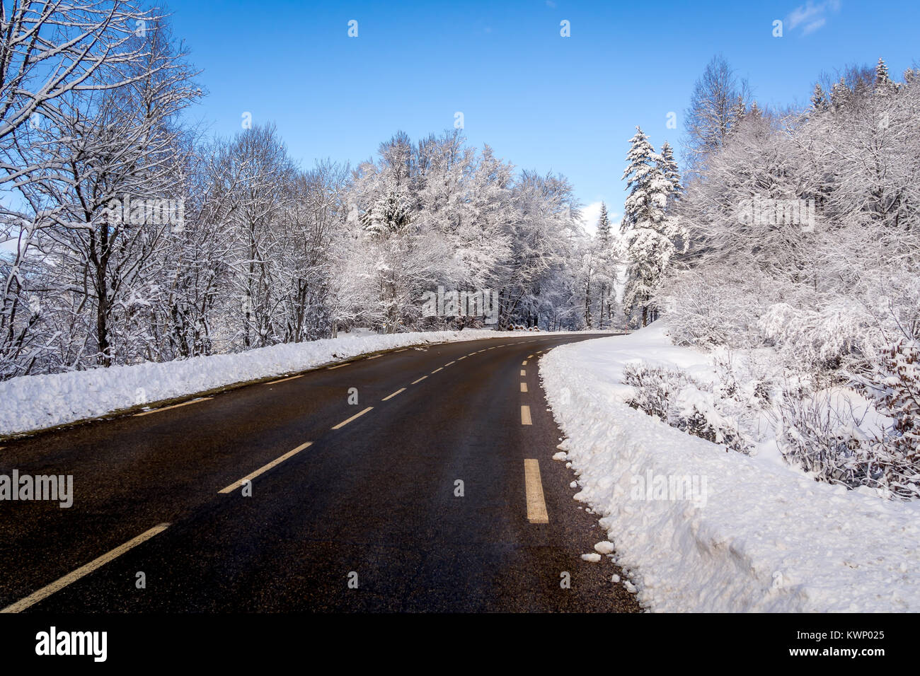 Snowy mountain road well cleared with a beautiful blue sky Stock Photo ...