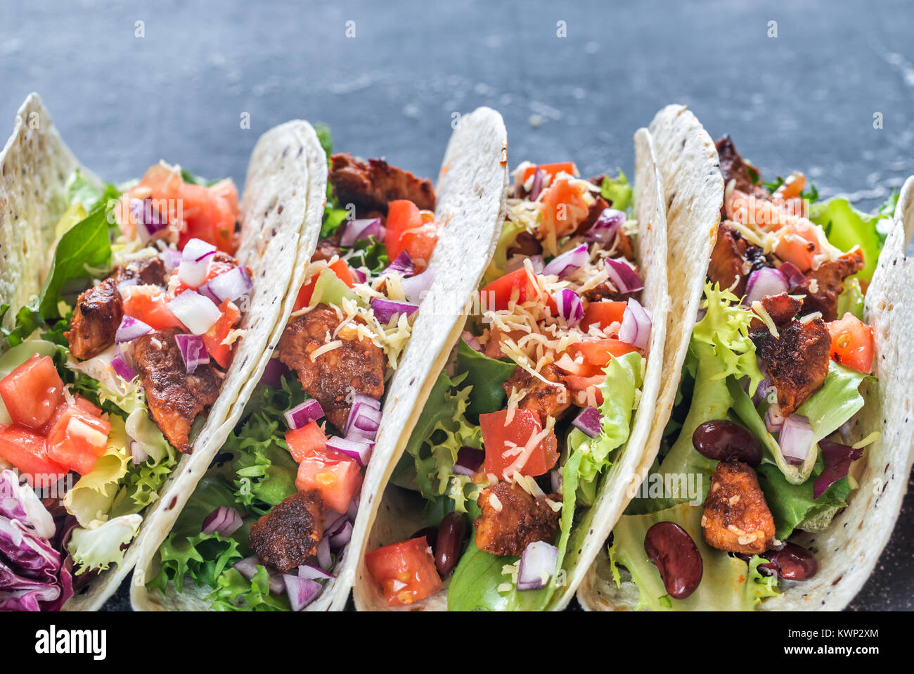 Four mexican tacos on a black background Stock Photo - Alamy