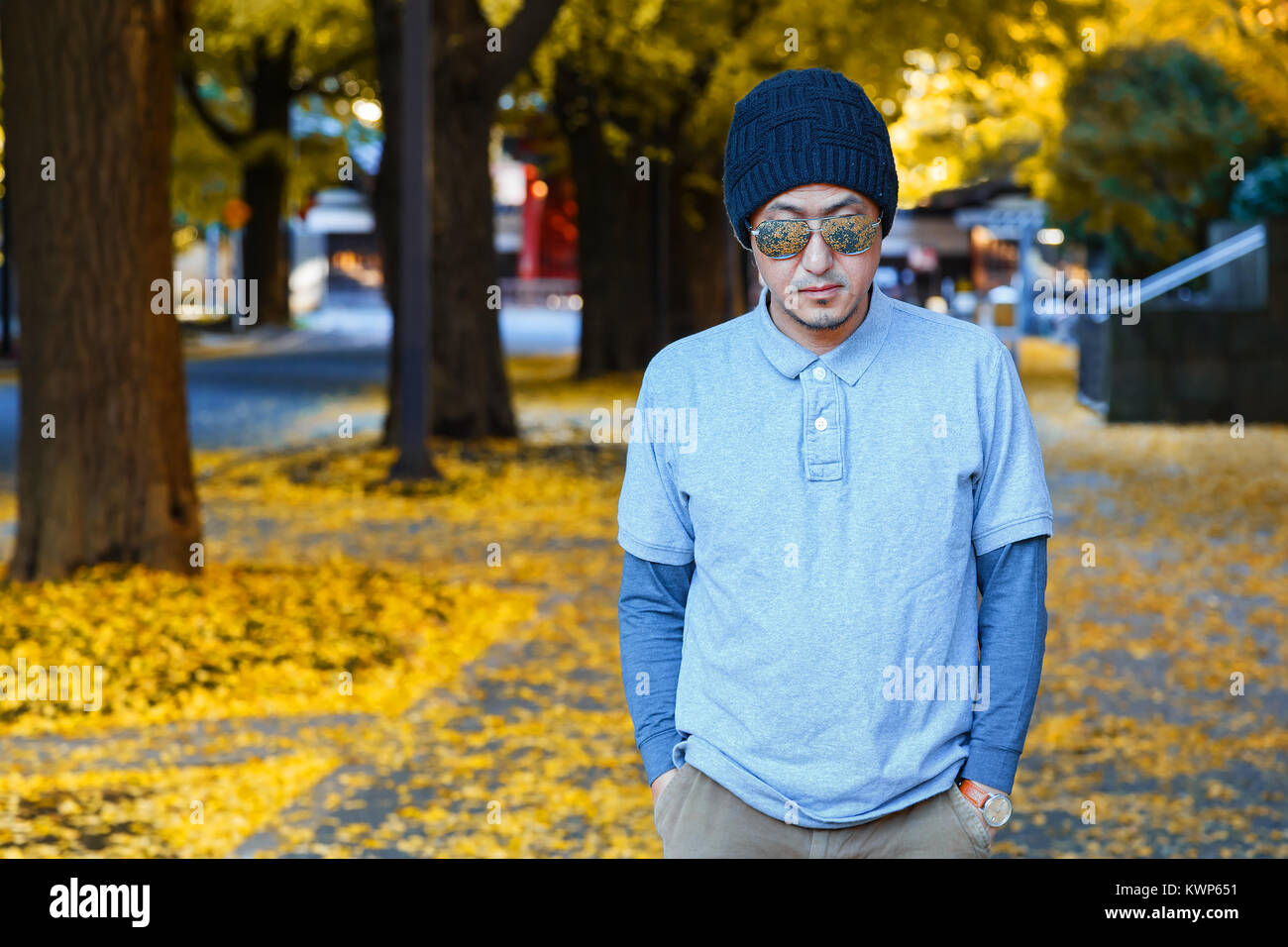 An asian man in a polo t-shirt walks on a street Stock Photo - Alamy