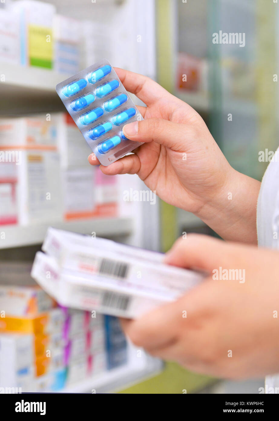 Pharmacist holding medicine box and capsule pack in pharmacy drugstore ...
