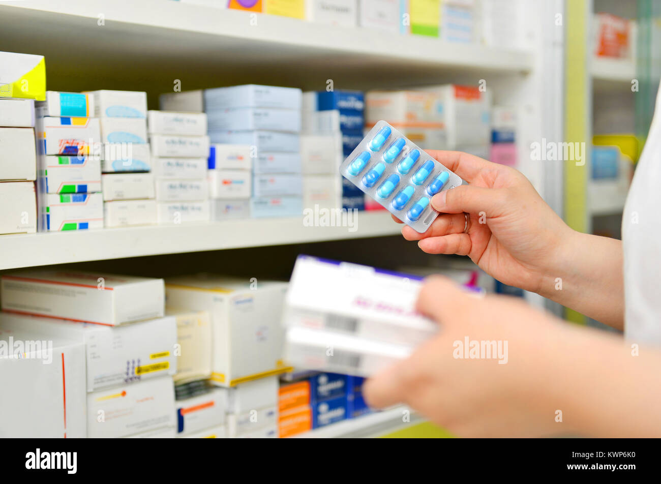 Pharmacist holding medicine box and capsule pack in pharmacy drugstore ...