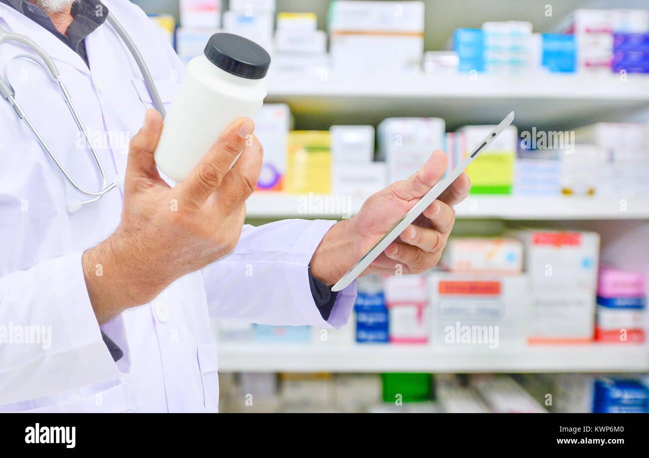 Pharmacist holding medicine bottle and computer tablet for filling ...