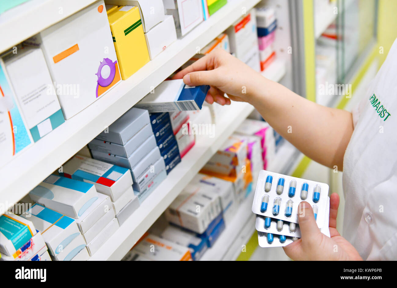 Pharmacist holding medicine box and capsule pack in pharmacy drugstore ...
