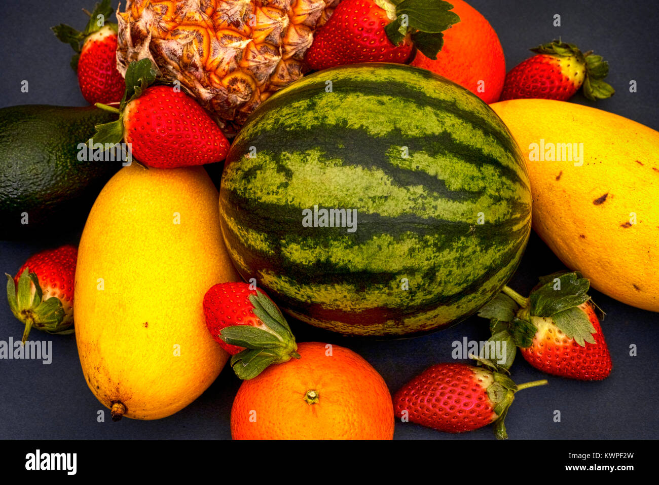 Watermelon, mango, strawberry, mandarin, pineapple and avocado on black ...