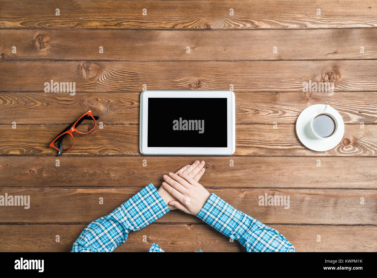 Top view of student sitting at wooden table and working with tablet ...