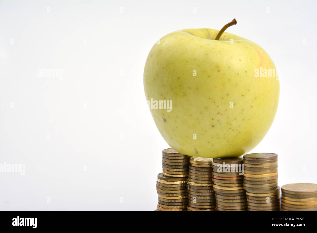 Yellow apple with coins isolated on white background Stock Photo - Alamy