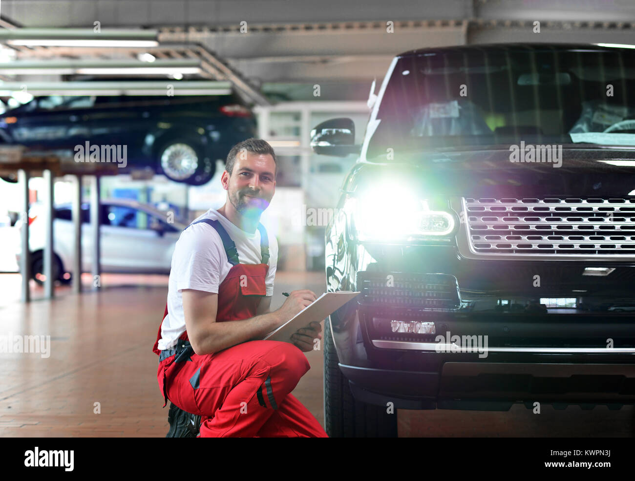 car repair shop - worker checks and adjusts the headlights of a car's ...