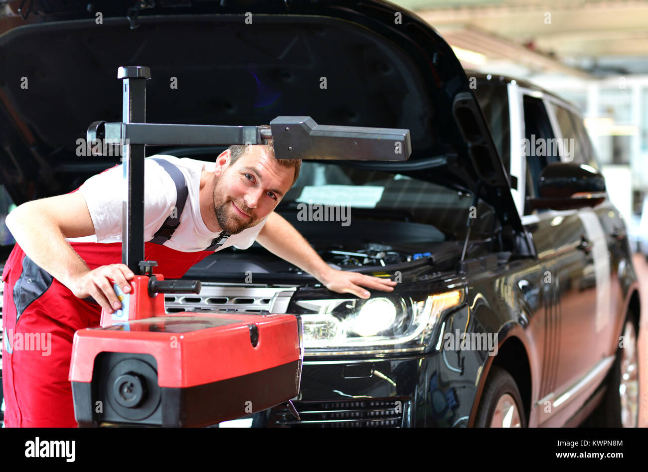 car repair shop - worker checks and adjusts the headlights of a car's ...