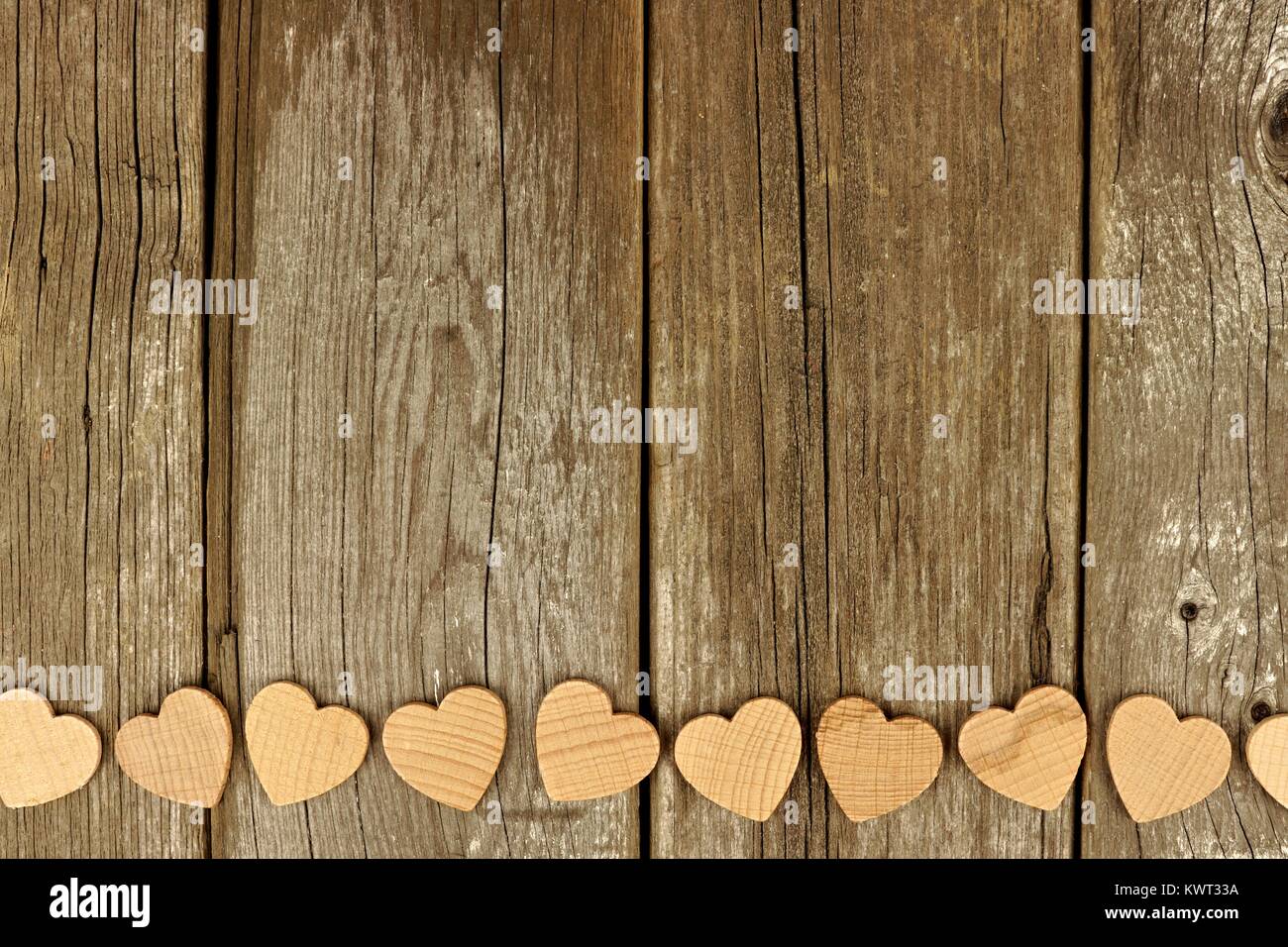 Valentines Day wooden hearts forming a bottom border on a rustic wood ...