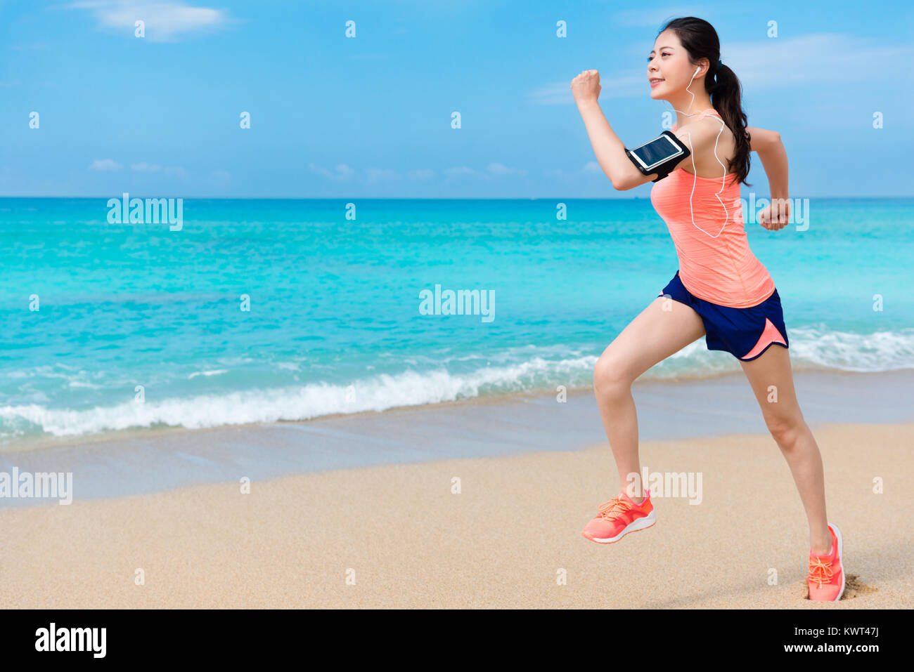 young happy female runner carrying earphones connecting mobile cell ...