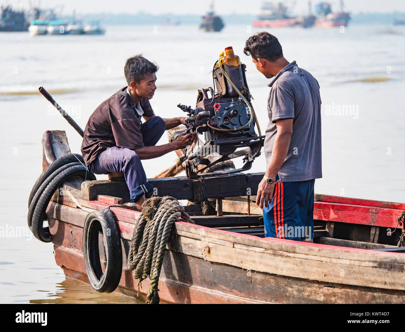 Two men reparing the engine of a traditional wooden boat before ...