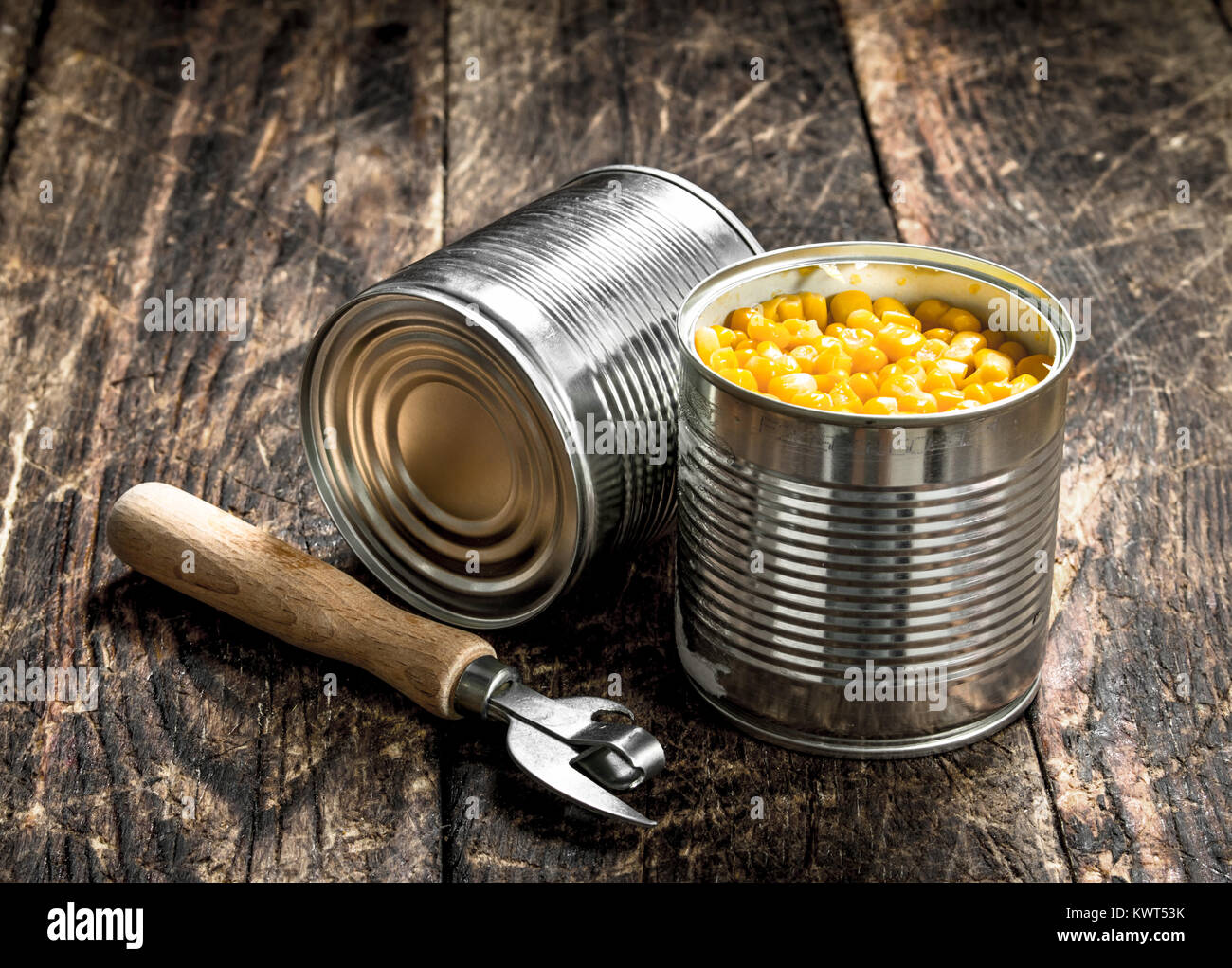 Canned corn in a tin can with opener. On a wooden background Stock ...