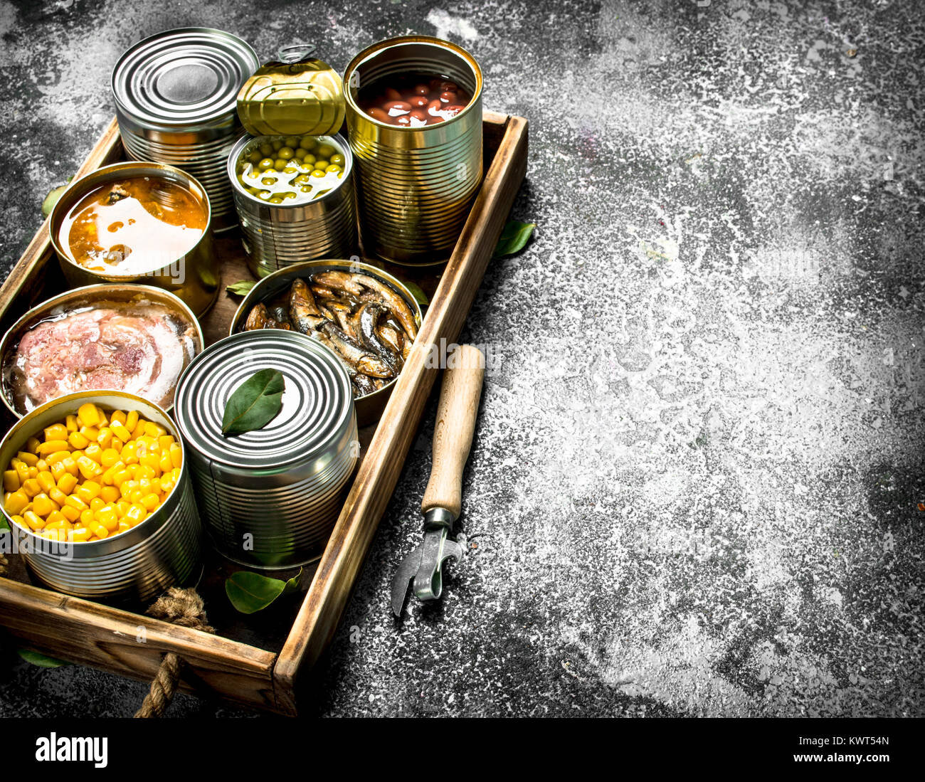 Various canned products in tin cans on a wooden tray. On a rustic ...