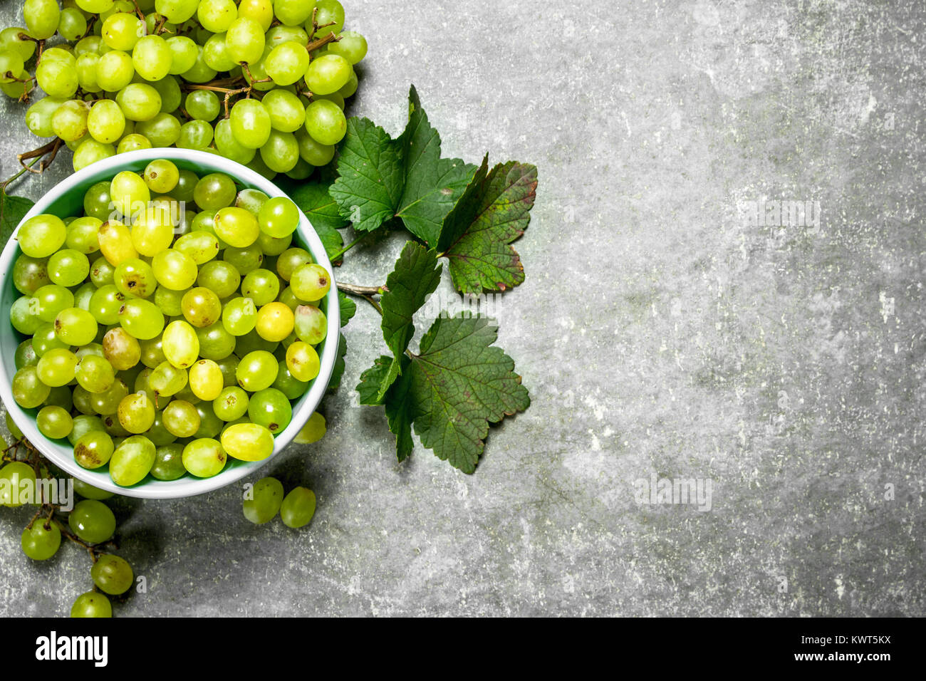 Green grapes in a bowl. On the stone table Stock Photo - Alamy
