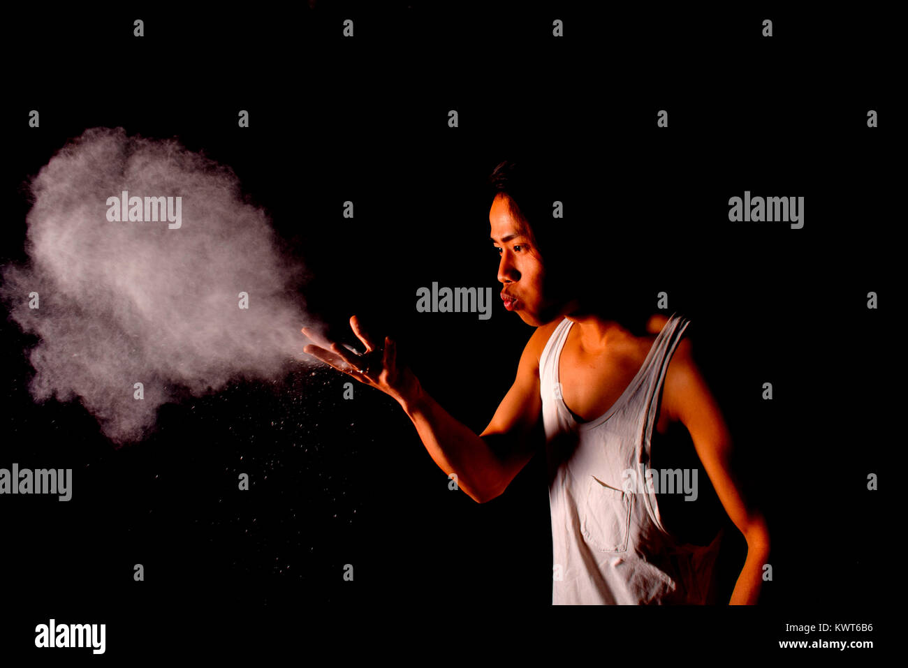 Young male in under-shirt or vest blowing powder, Pune, Maharashtra ...