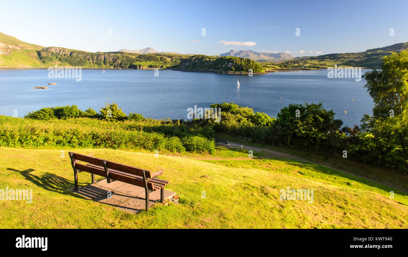 A hillside bench for weary walkers looks out across Portree Bay to the ...