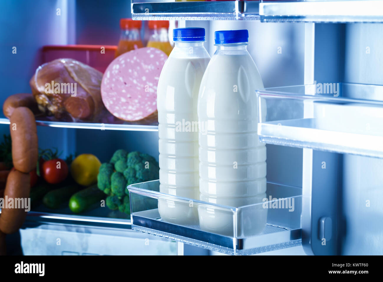 Open refrigerator filled with food. Focus on Bottles of milk in the ...