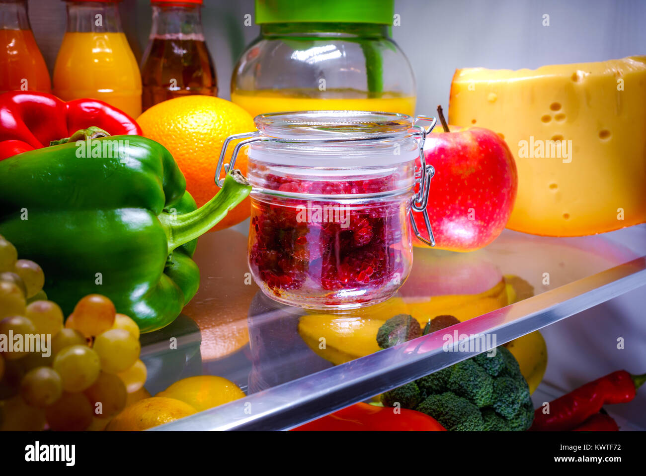 Fresh raspberries in a glass jar on a shelf open refrigerator. Healthy ...