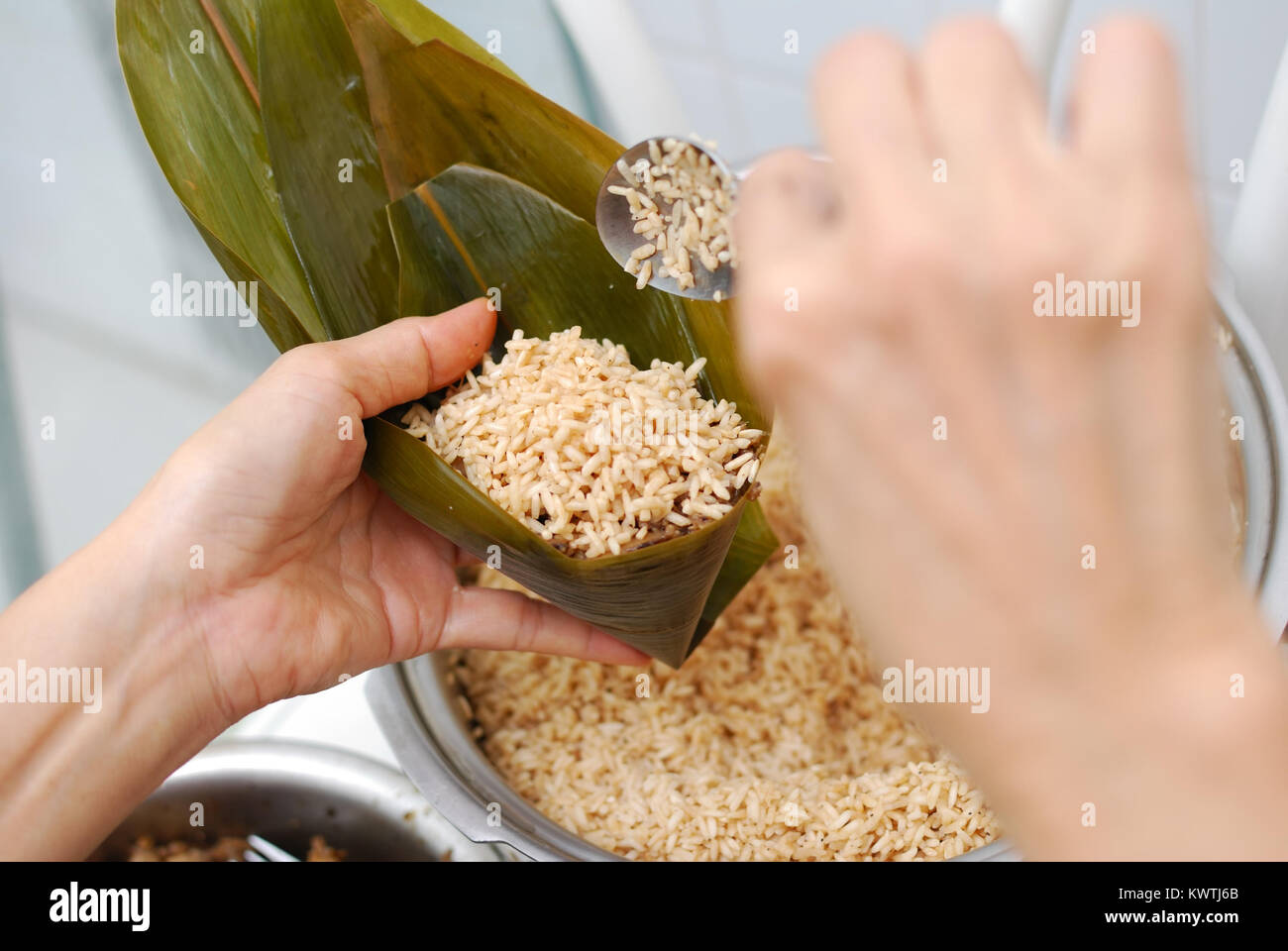 Filling rice into a triangular cone made from bamboo leaves. Asian ...