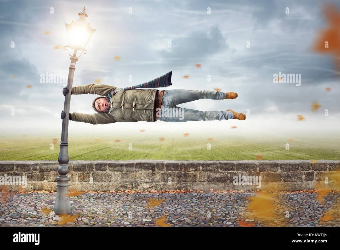 Man holding on to a street lamp during a storm Stock Photo - Alamy