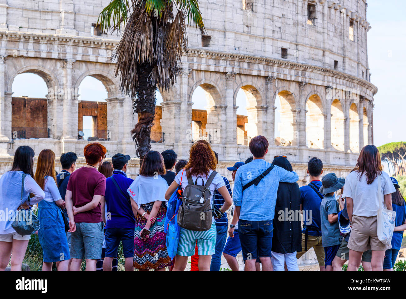 Tourists admire the Colosseum, while the tour guide provides historical ...