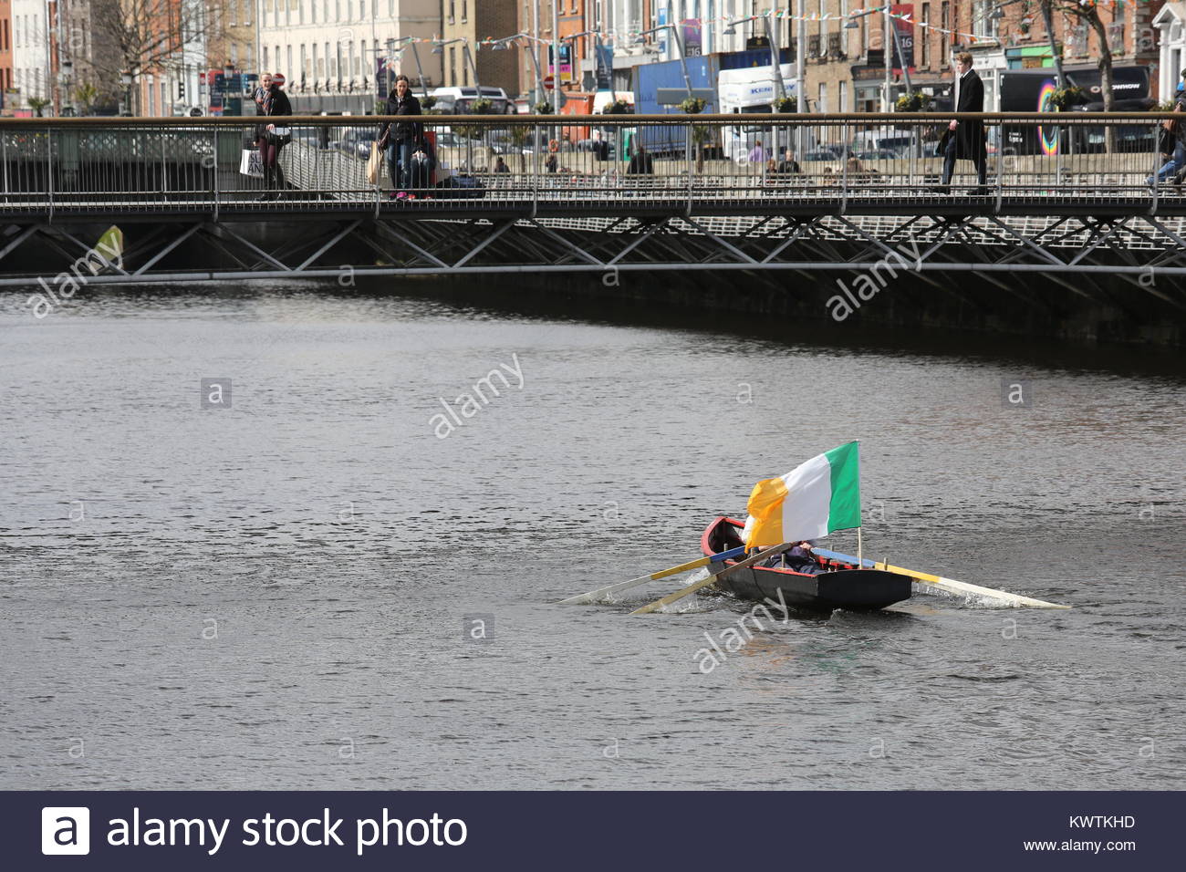 An Irish flag on the back of a small boat sailing up the River Liffey ...