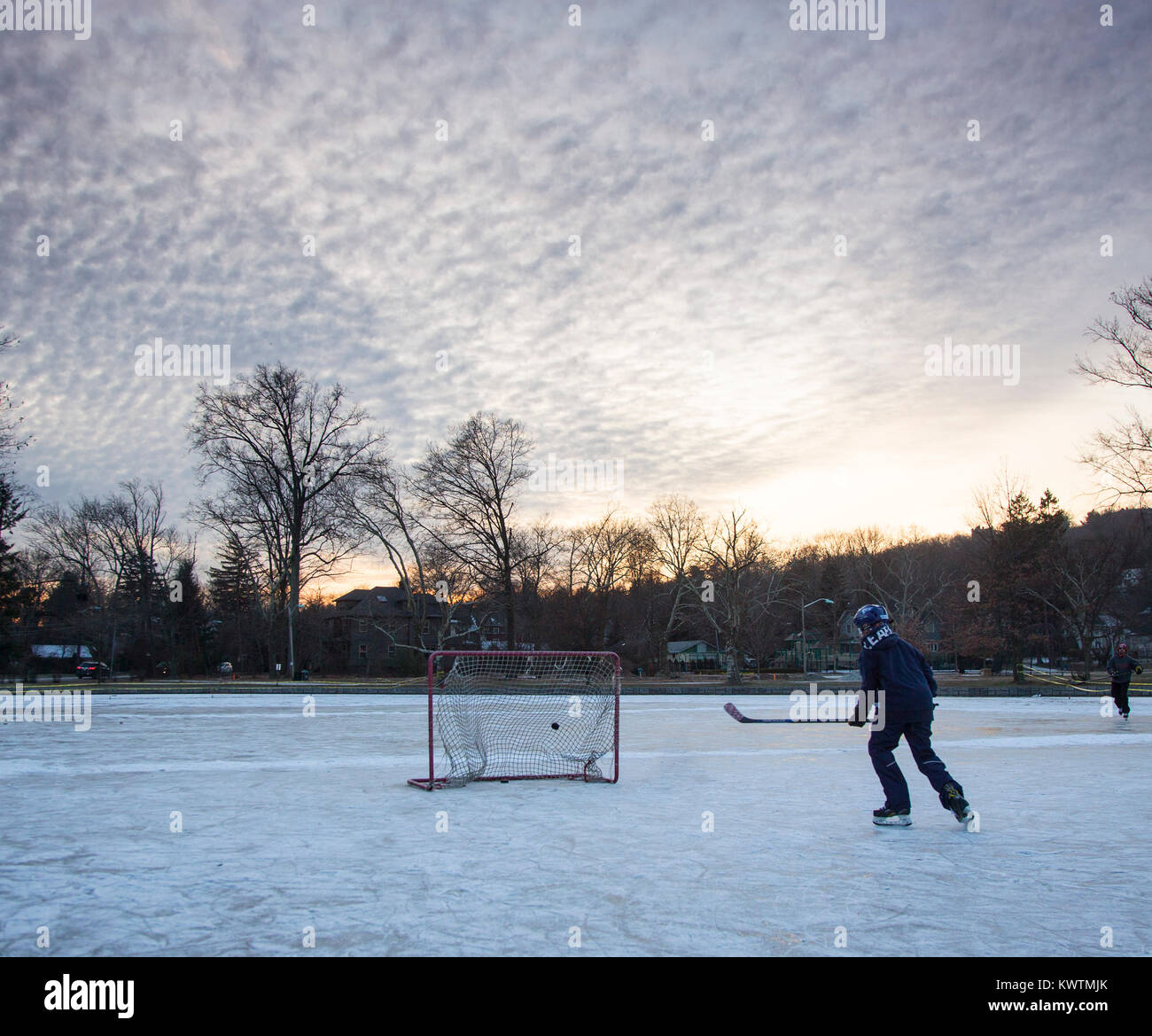 Ice hockey player shooting a puck on a frozen pond Stock Photo - Alamy