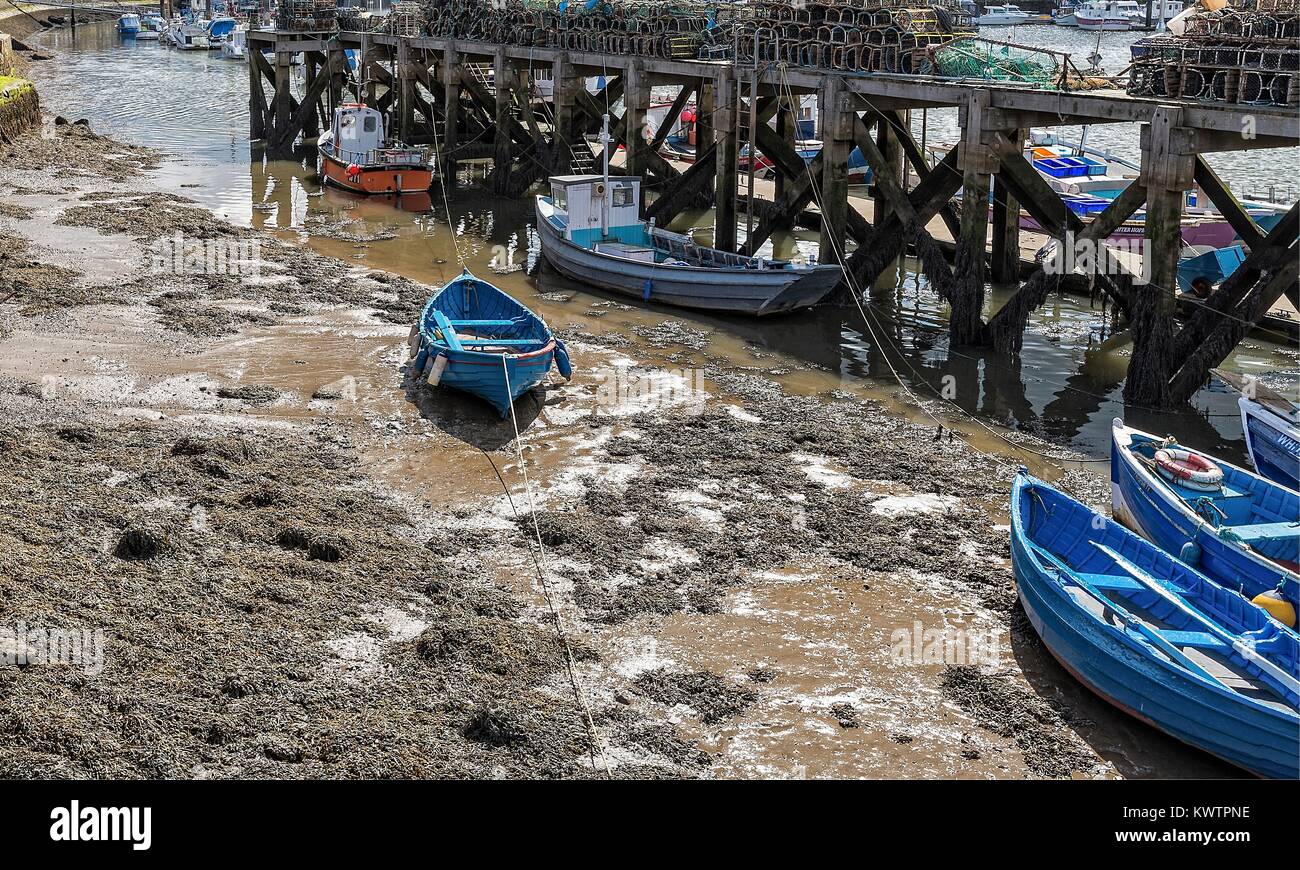 Boats stranded at low tide beneath a wooden jetty Stock Photo - Alamy
