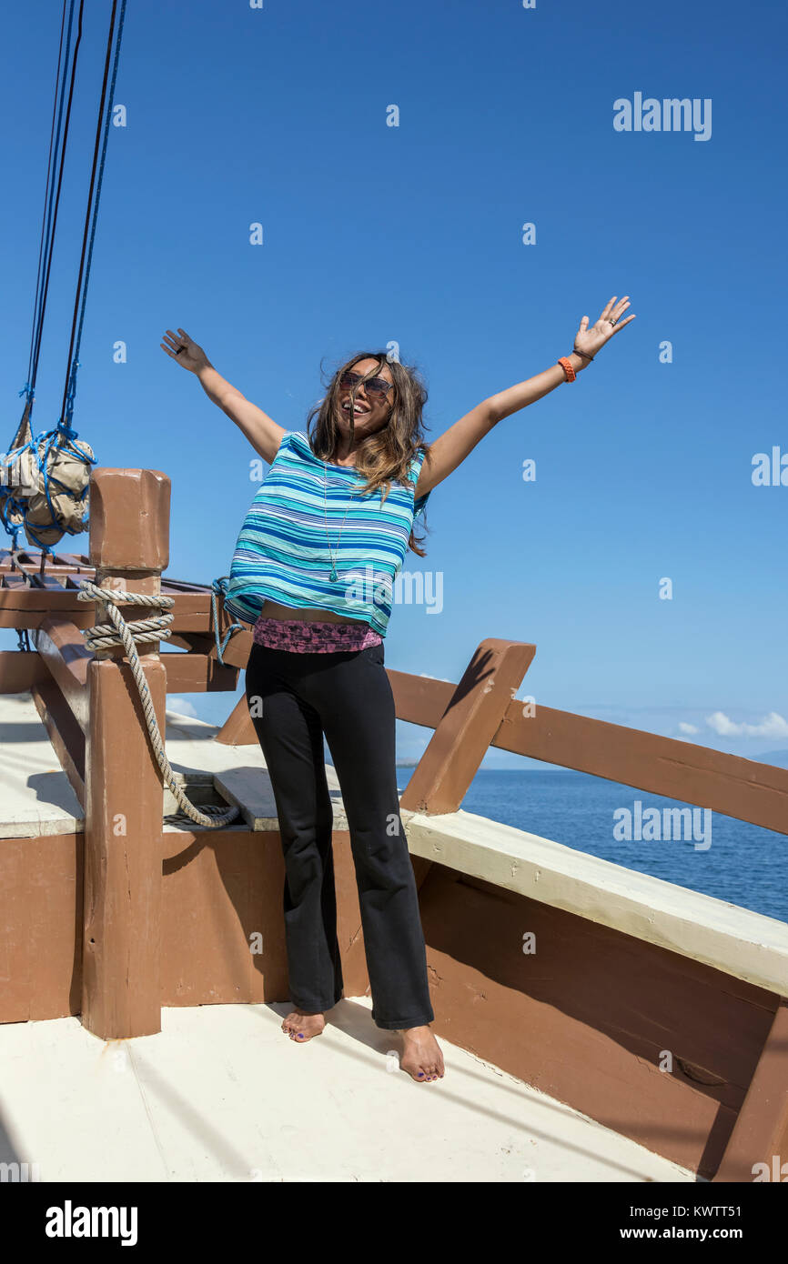 Joy of sailing, woman on old pinisi-style wooden boat, off Labuan Bajo ...