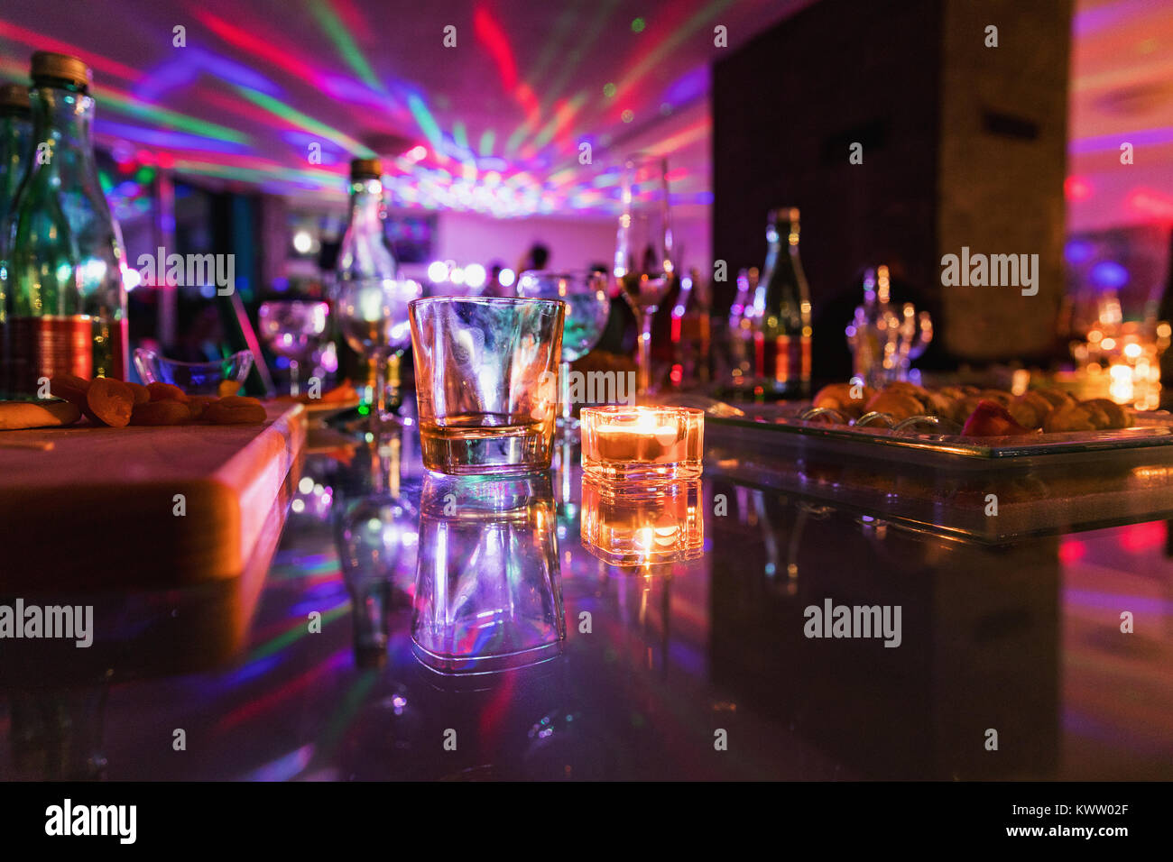 Colorful glasses on a glass bar illuminated by light, abstract ...