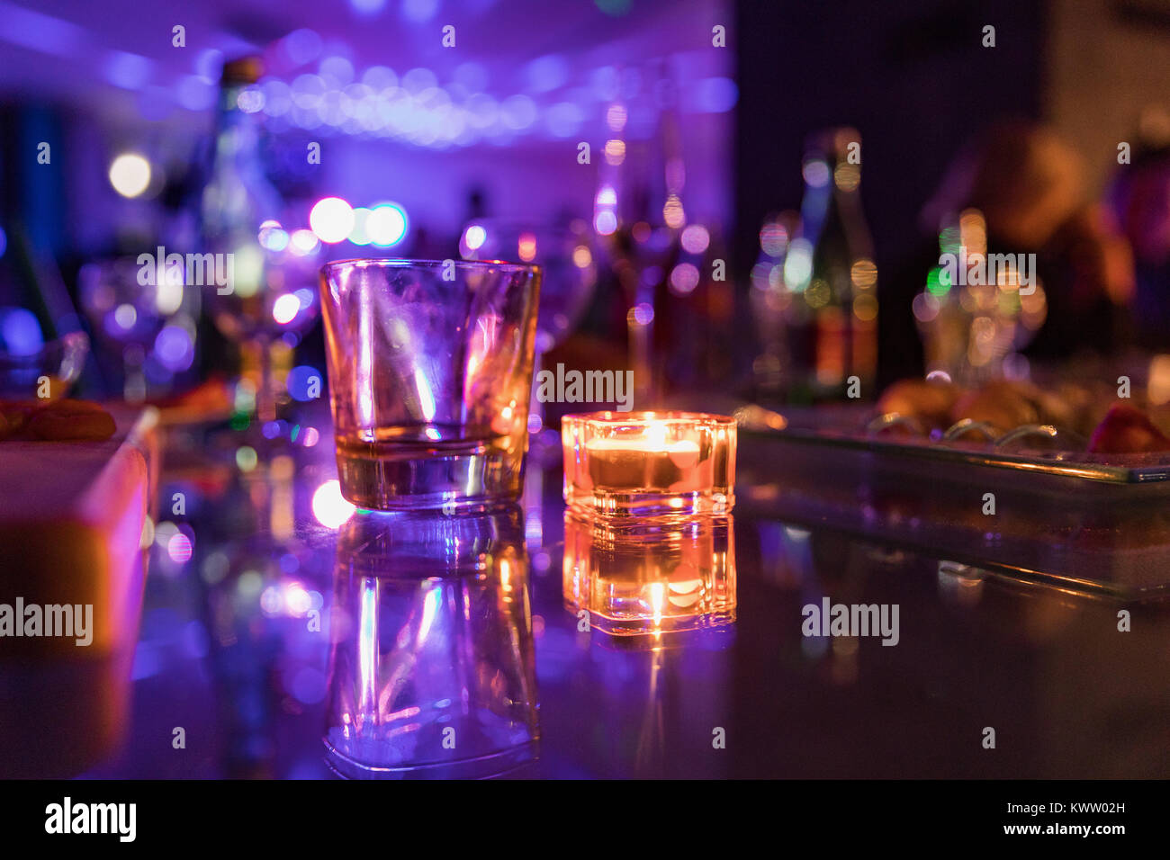 Colorful glasses on a glass bar illuminated by light, abstract ...