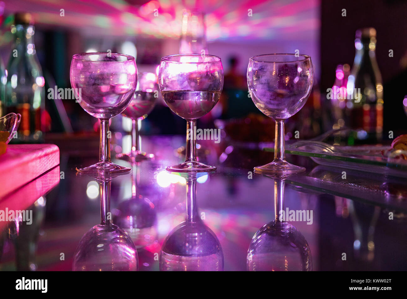 Colorful glasses on a glass bar illuminated by light, abstract ...