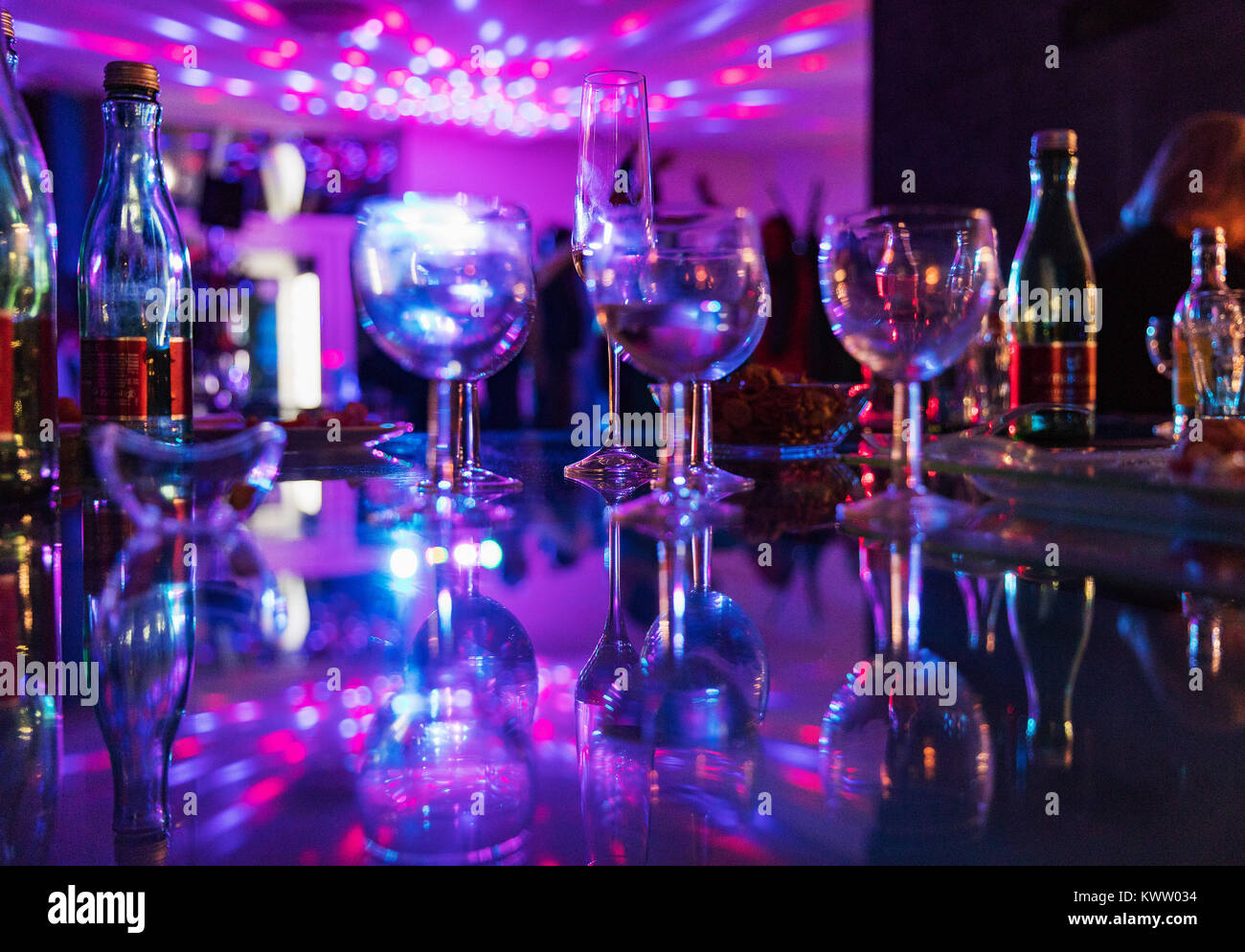 Colorful glasses on a glass bar illuminated by light, abstract ...