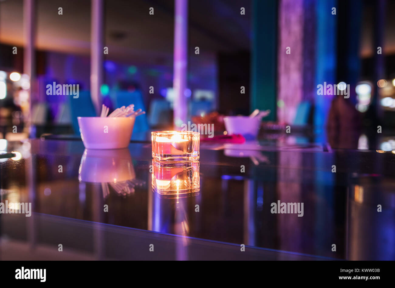 A burning candle on a glass bar illuminated by light, abstract ...