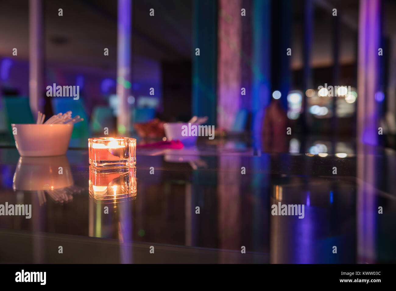 A burning candle on a glass bar illuminated by light, abstract ...