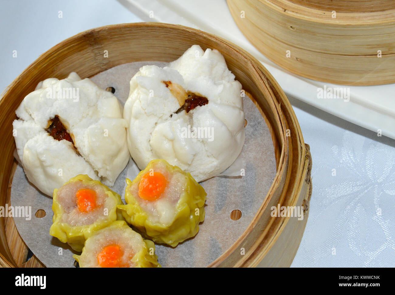 Dim sum, Dumplings and Chinese buns on plate in bamboo basket Stock ...