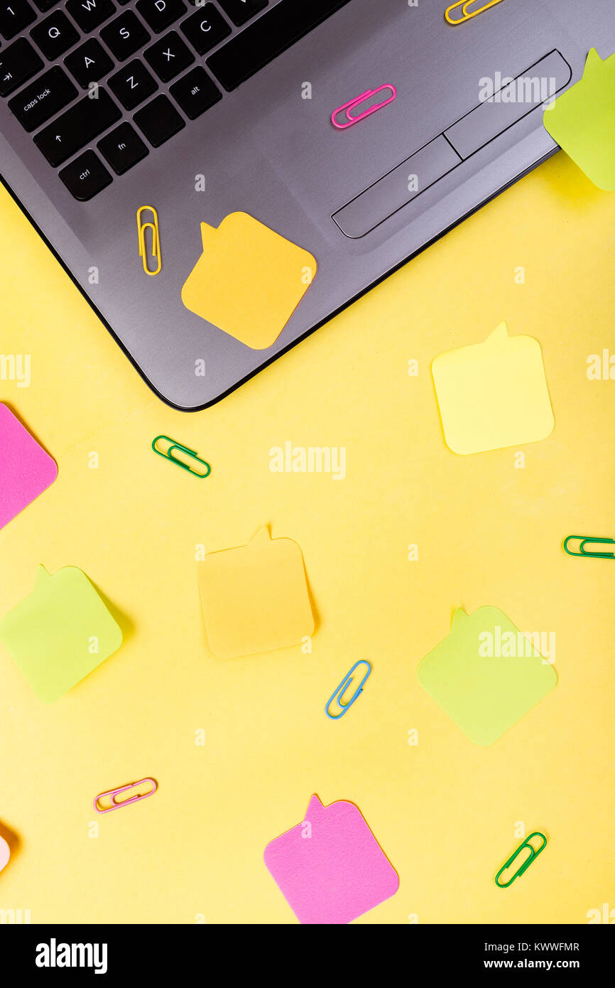 Notebook with colorful stickers on yellow paper background. Workplace ...