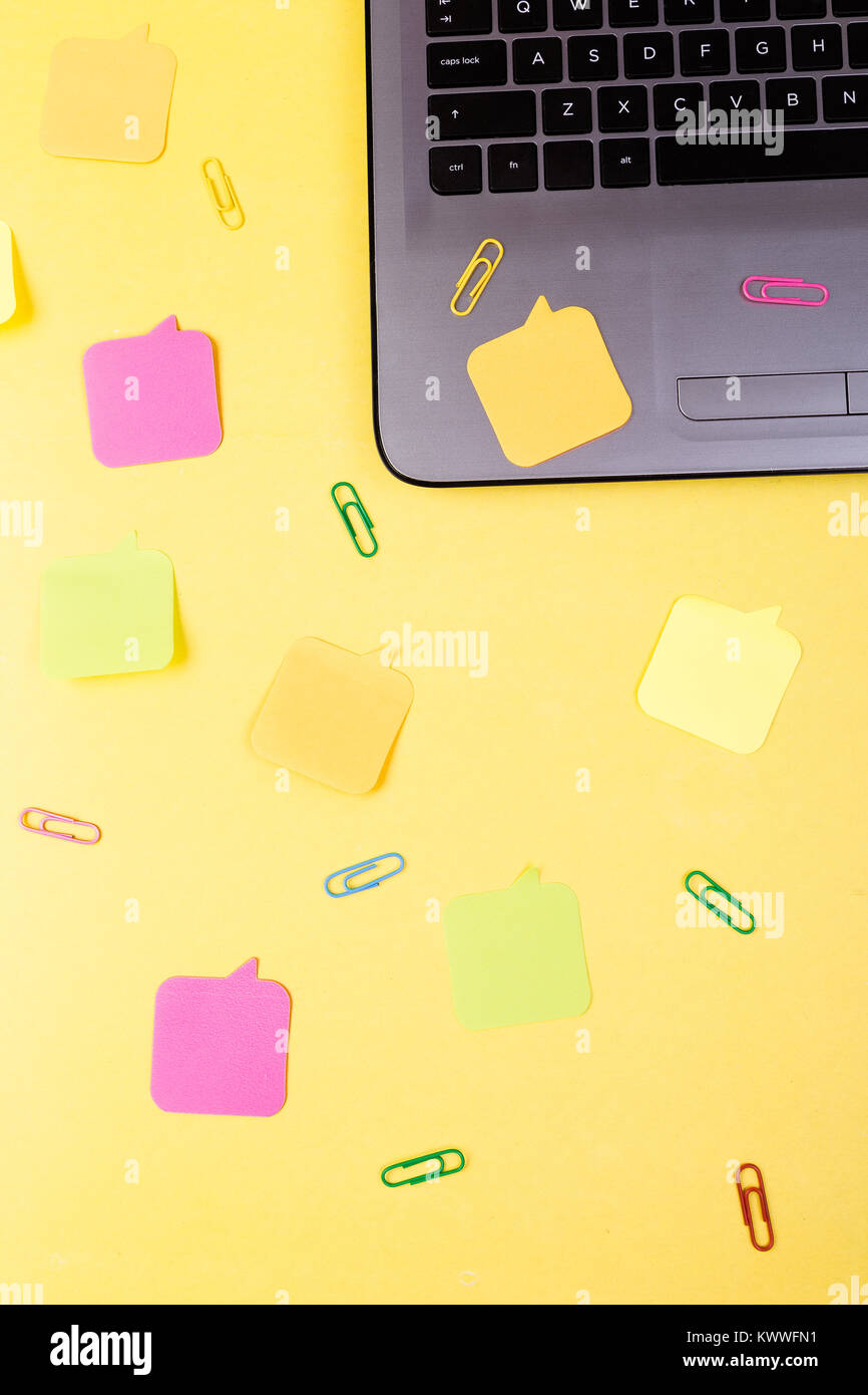 Notebook with colorful stickers on yellow paper background. Workplace ...
