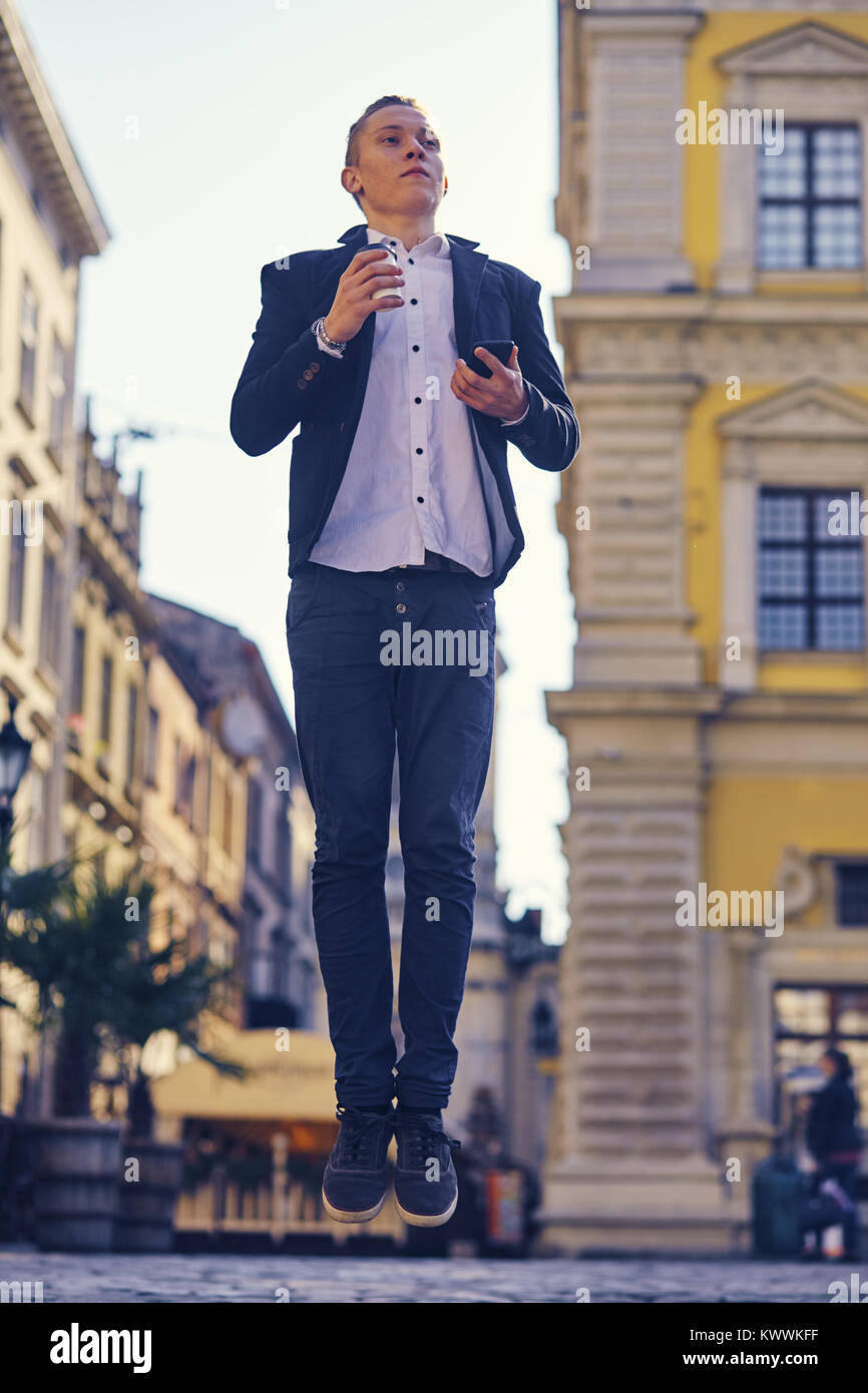 man jumping in the street while holding cup of coffee Stock Photo - Alamy