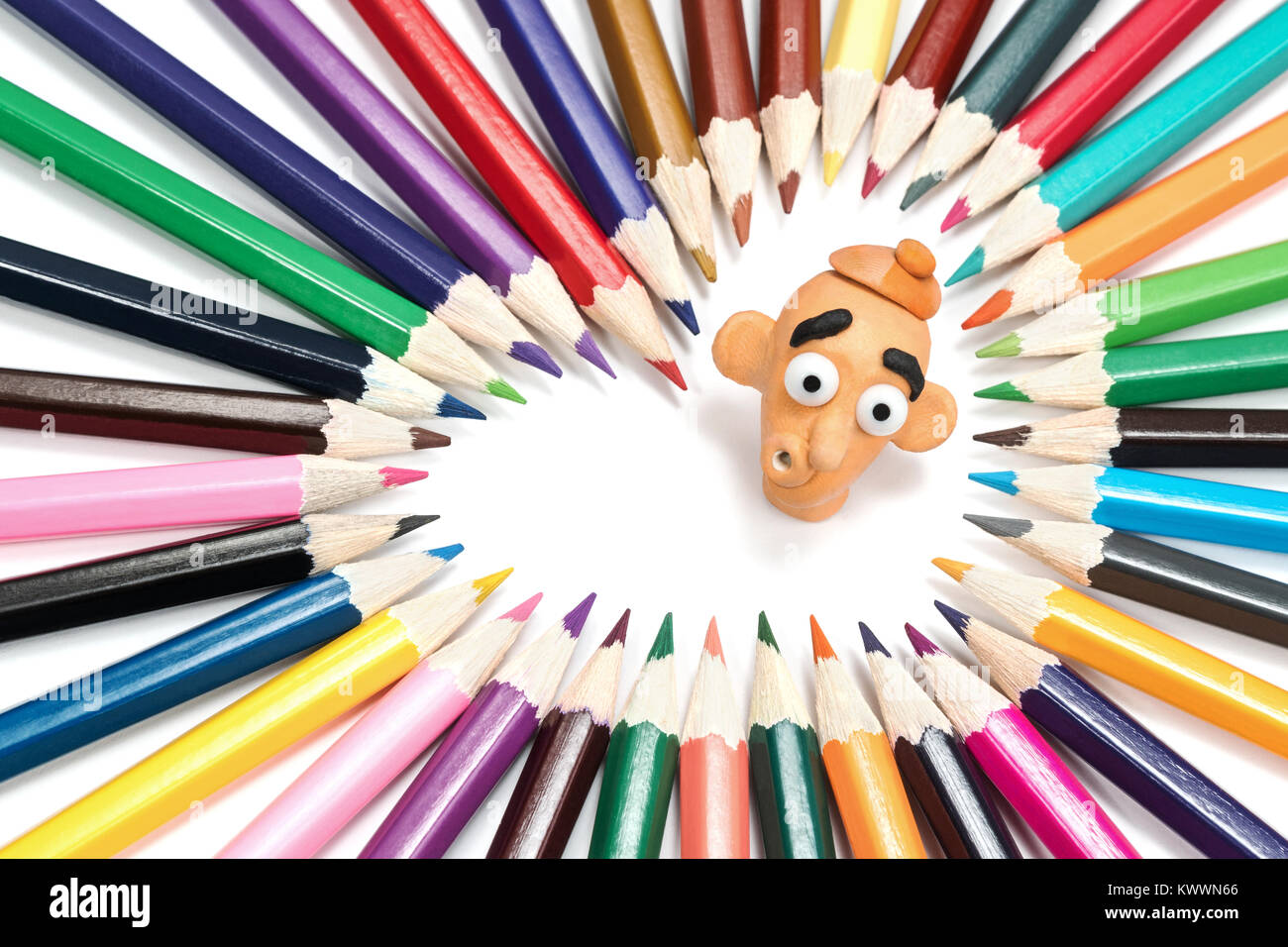 Surprised plasticine head of an artist among pencils lined in the shape ...