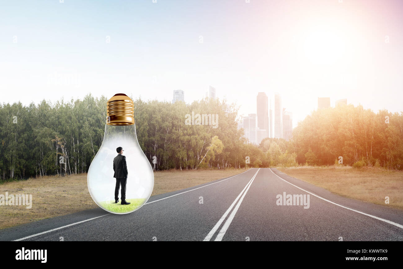 Young businessman trapped inside of light bulb on asphalt road Stock ...