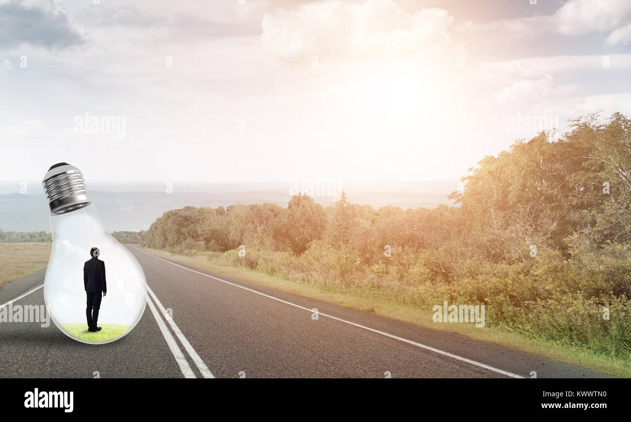 Young businessman trapped inside of light bulb on asphalt road Stock ...