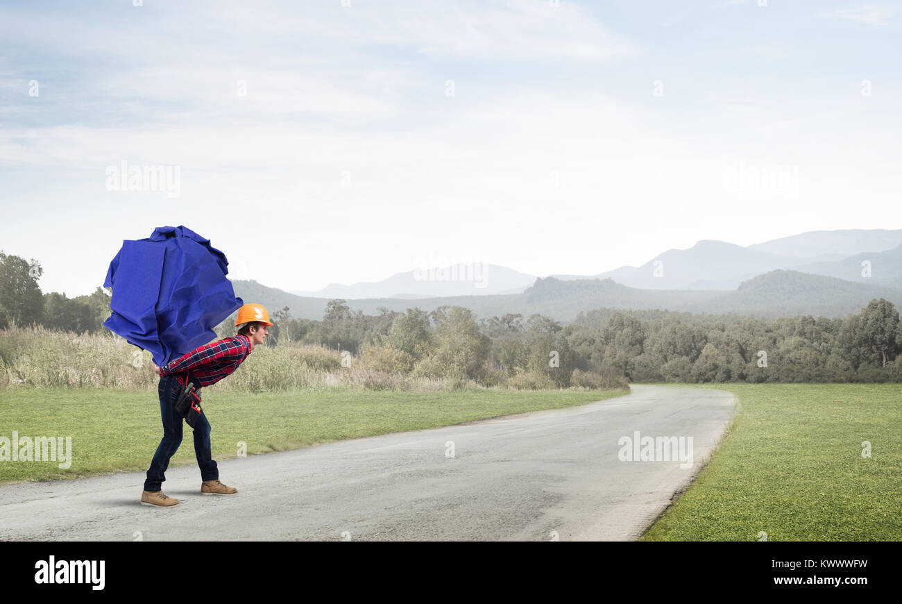 Builder man carrying paper ball on his back Stock Photo - Alamy