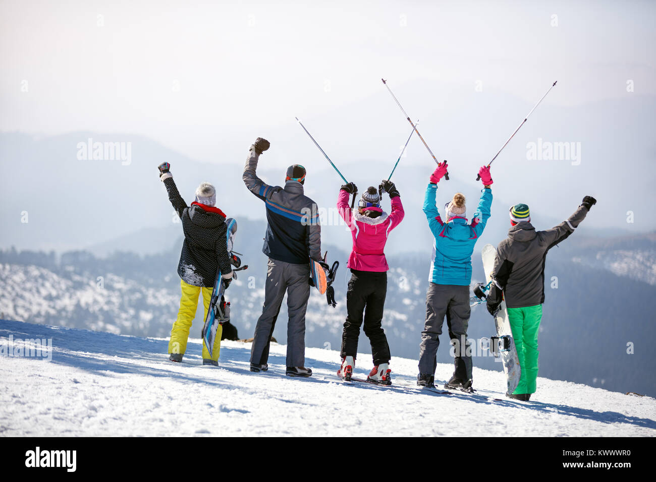 Back view of group skiers with hands and ski sticks up in mountain ...