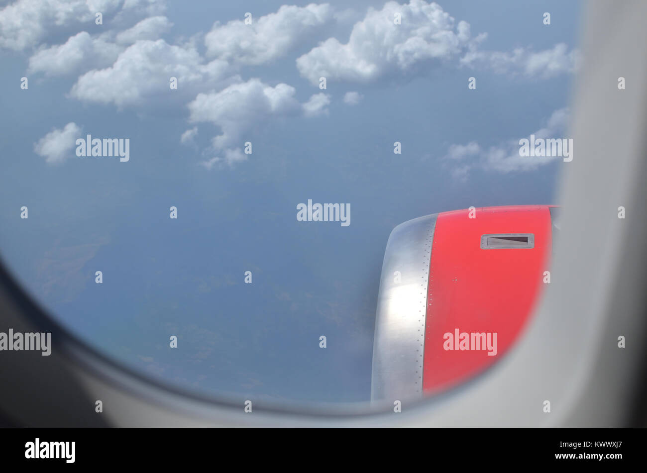 View through airplane window to its engine and clouds in distance ...