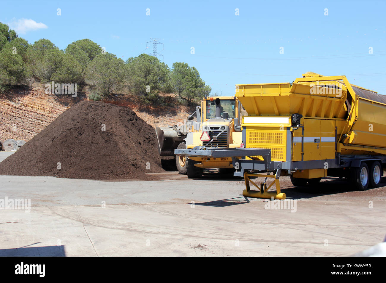 Industrial compost grinder fed by a bulldozer mulching garden waste ...