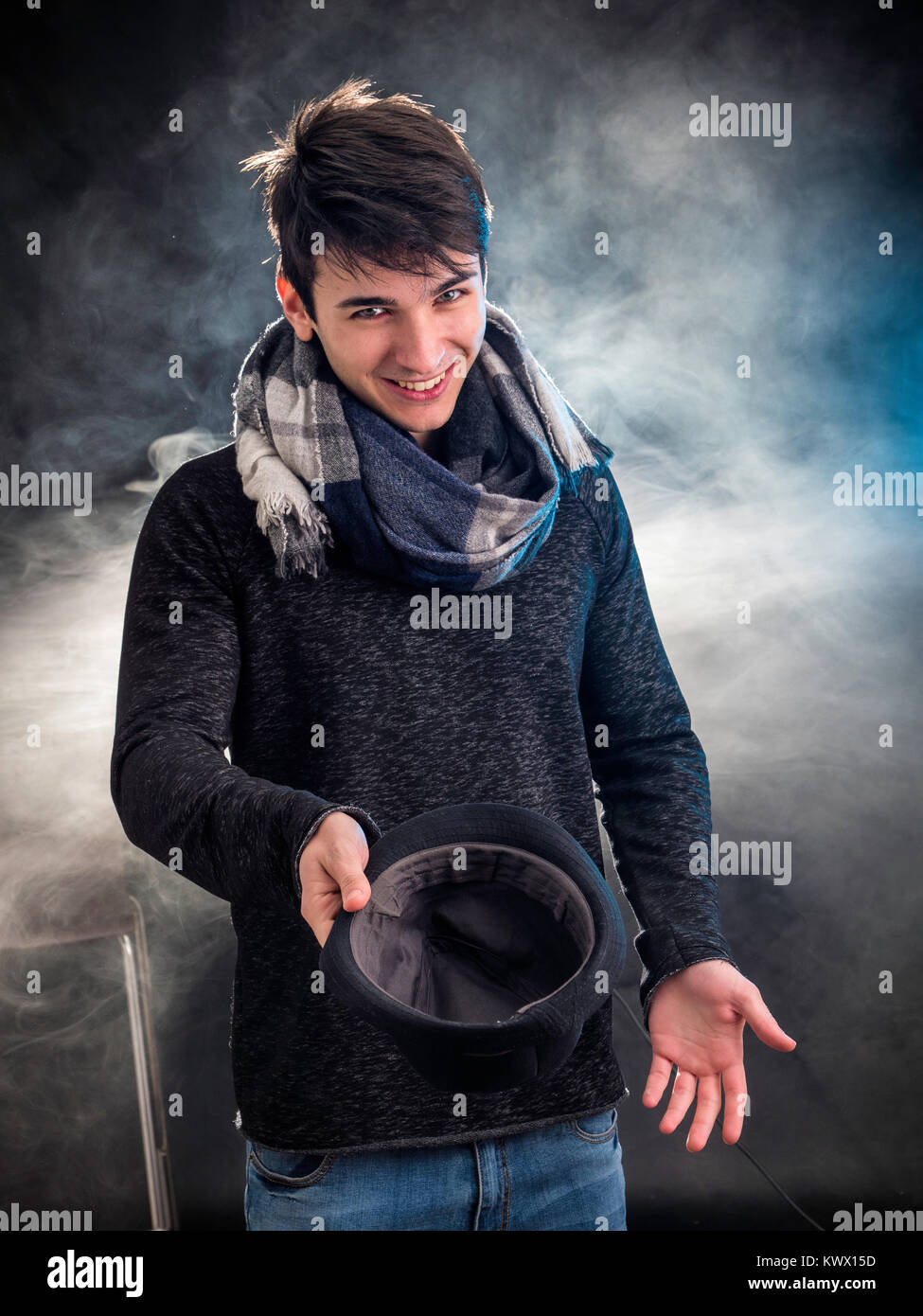 Cheerful young man posing and begging with hat in studio Stock Photo ...